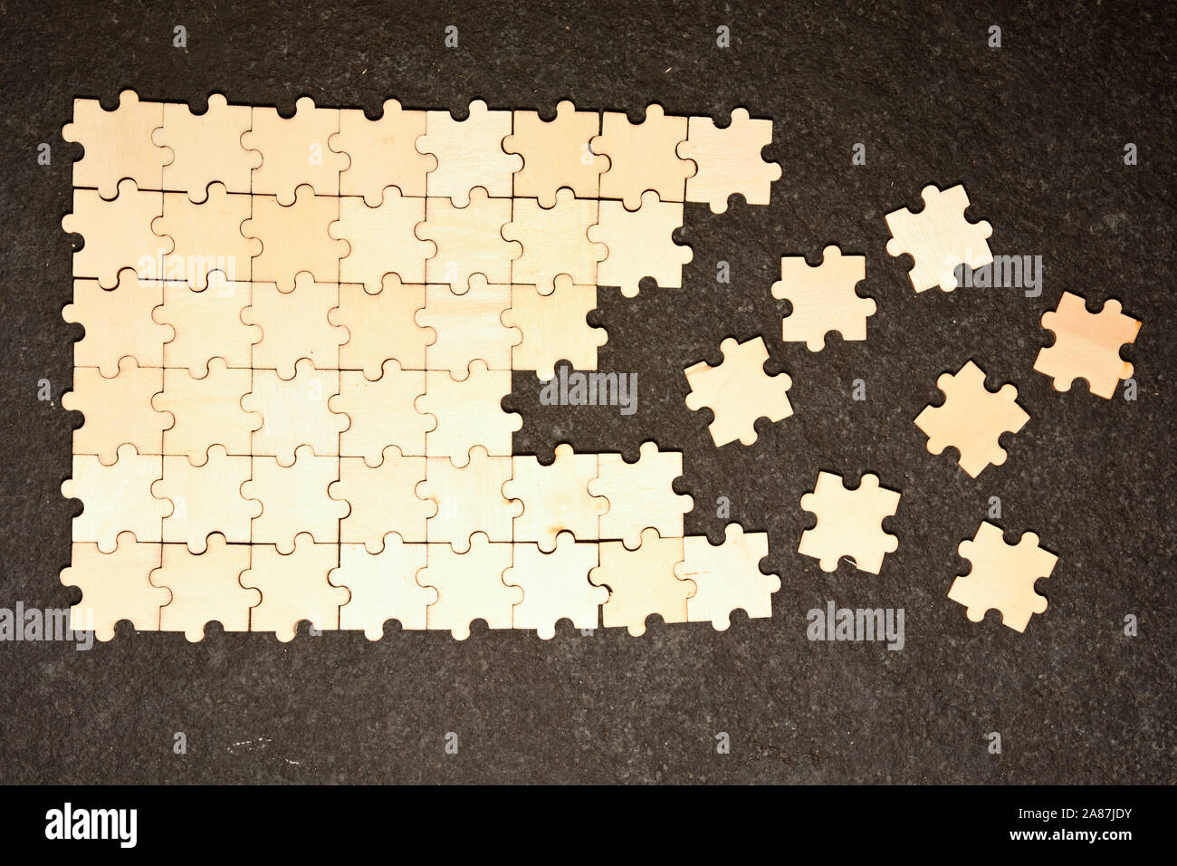 Half ordered puzzle with white jigsaw pieces. One side of the image ...