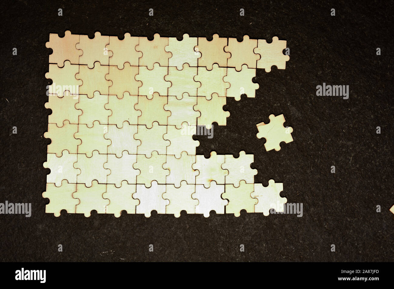 Half ordered puzzle with white jigsaw pieces. One side of the image ...