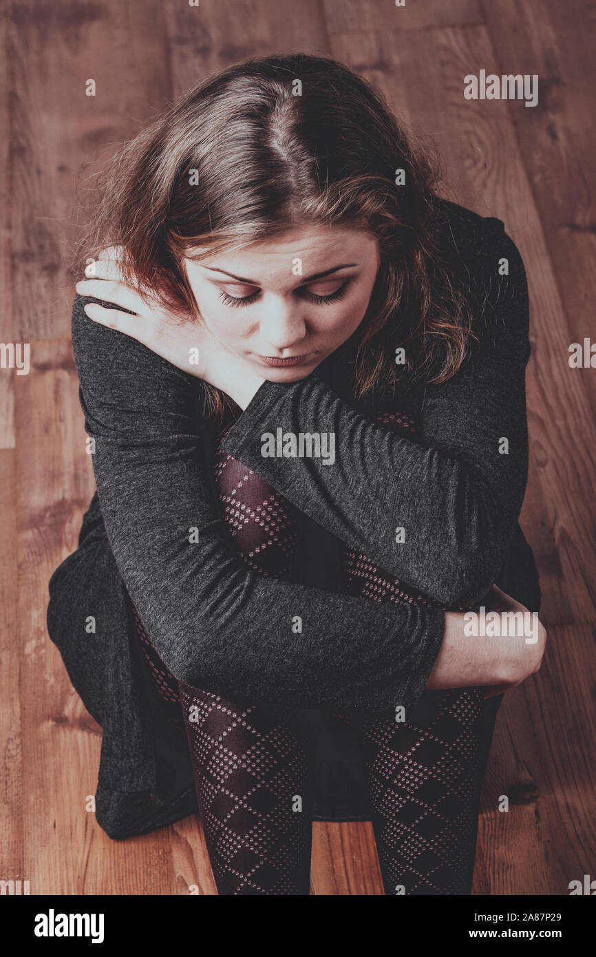 Sad or depressed woman sitting on the floor. Top view of lonely woman ...