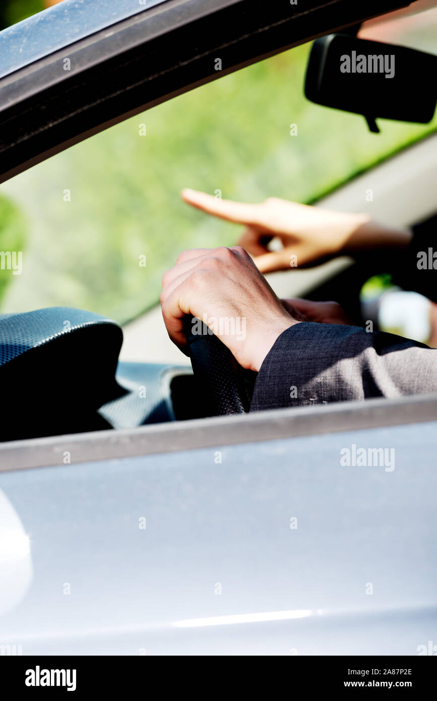 Man driving car and woman shows him direction. Inside car on men hands ...