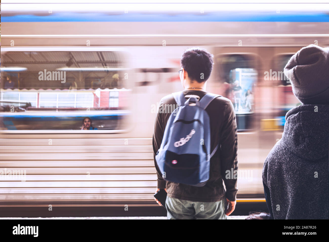 Back of a man waiting for the train under the sunlight at station in ...