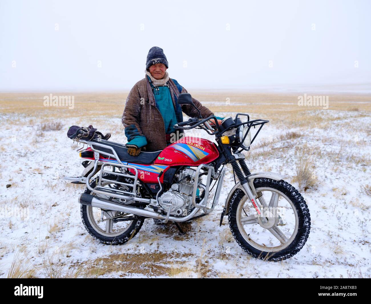 Old man with his motorcycle in a blizzard, Mongolian steppe, Bulgan ...