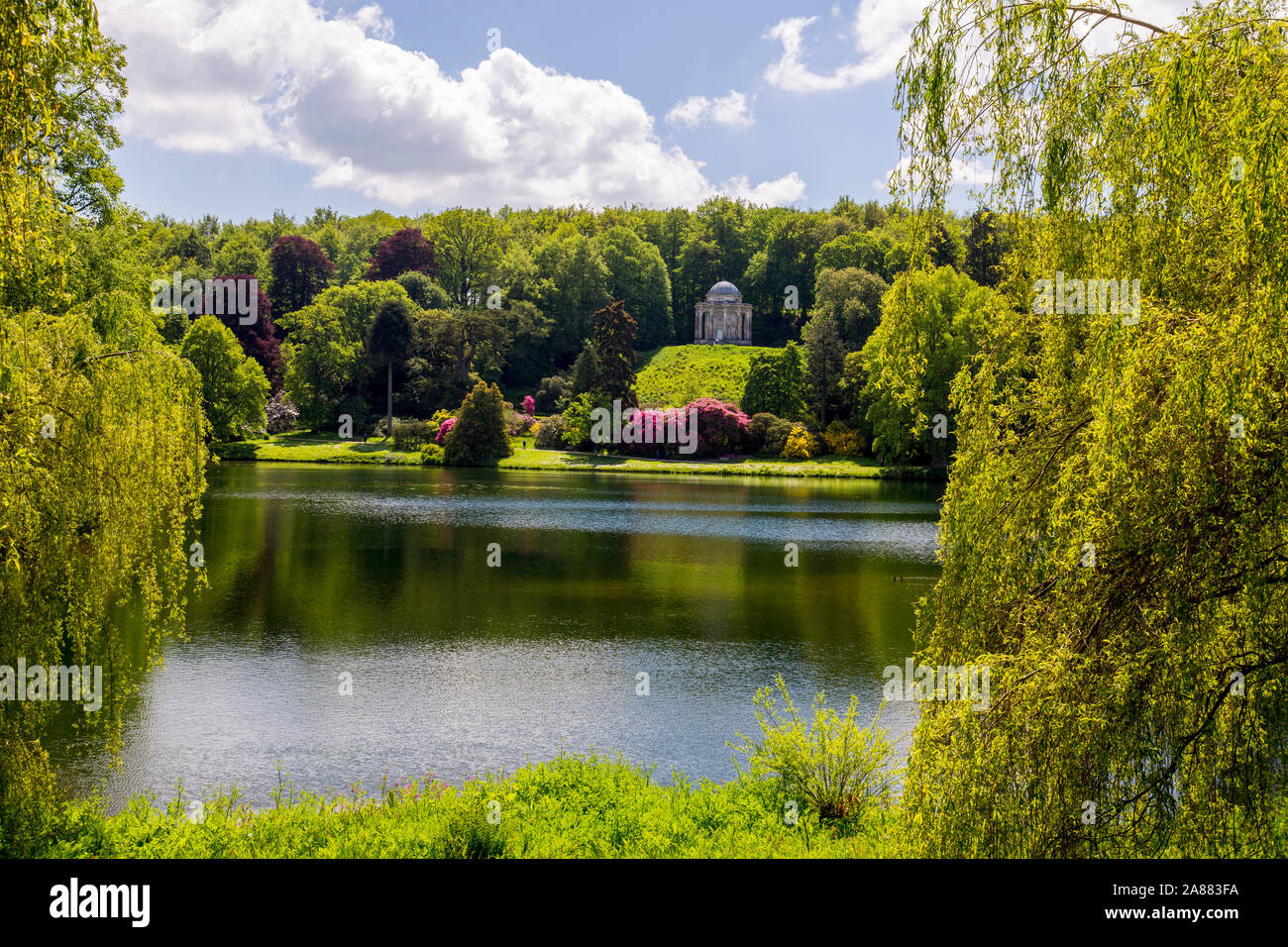 The circular Temple of Apollo looks out over colourful rhododendron ...
