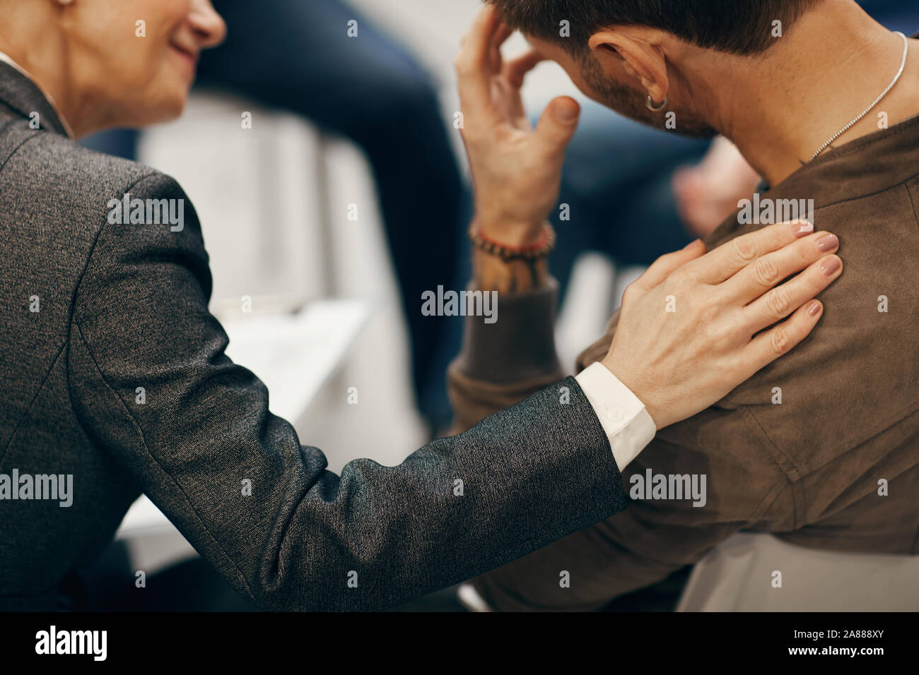 Rear view of mature woman supporting young man she touching his ...