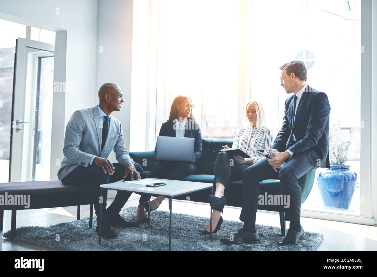 Smiling group of diverse businesspeople talking together while sitting ...