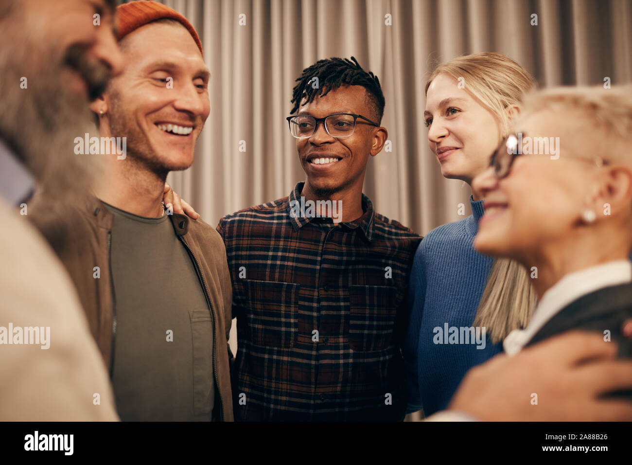 Group of people standing smiling to each other and talking during their ...