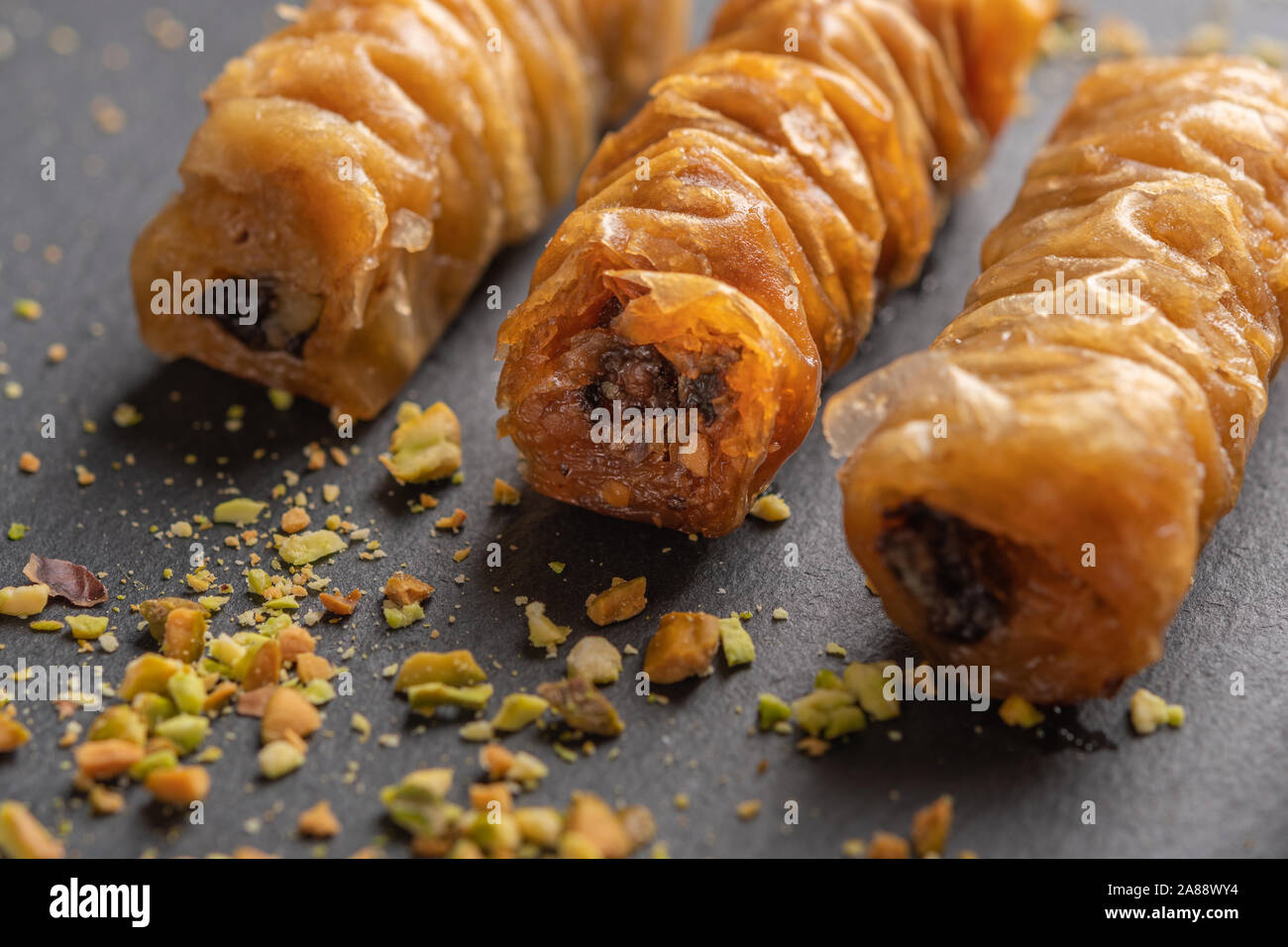 Traditional greek pastries saragli with pistachios on dark background ...