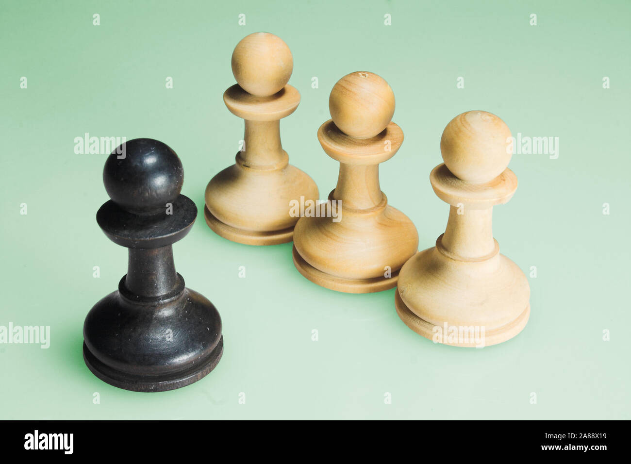 four chess pieces in front of a mint-coloured background. one black ...