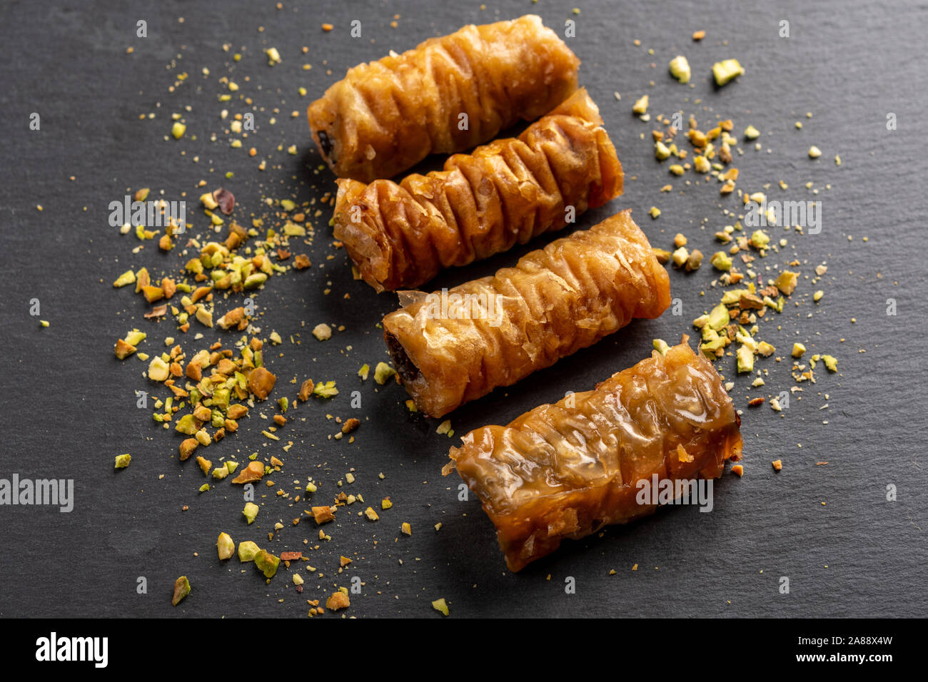 Traditional greek pastries saragli with pistachios on dark background ...