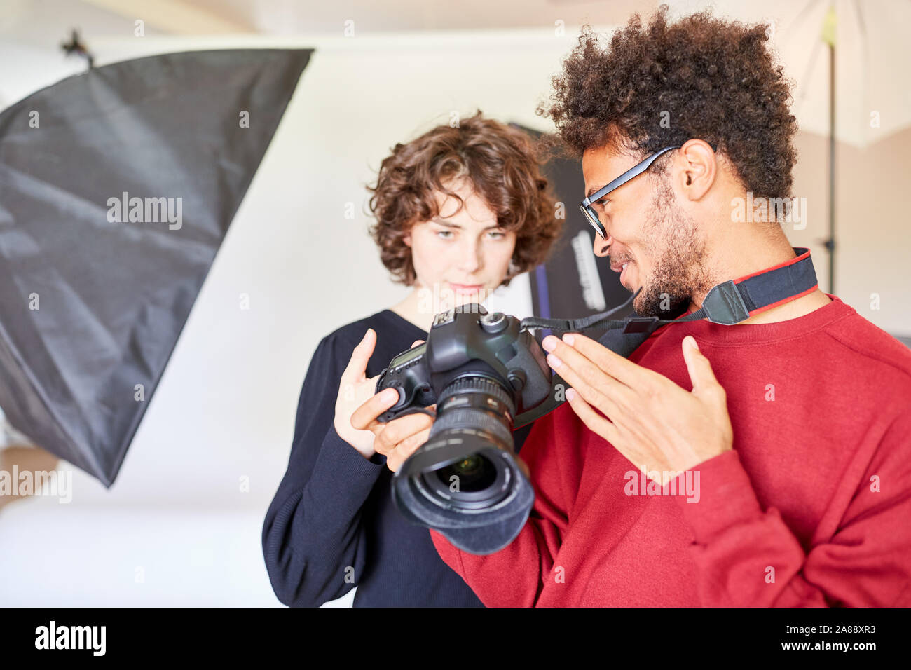 Photographer and photo assistant with reflex camera in the photo studio ...