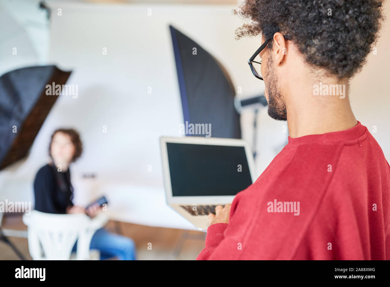 Young photographer at the laptop computer is preparing a photo shoot ...