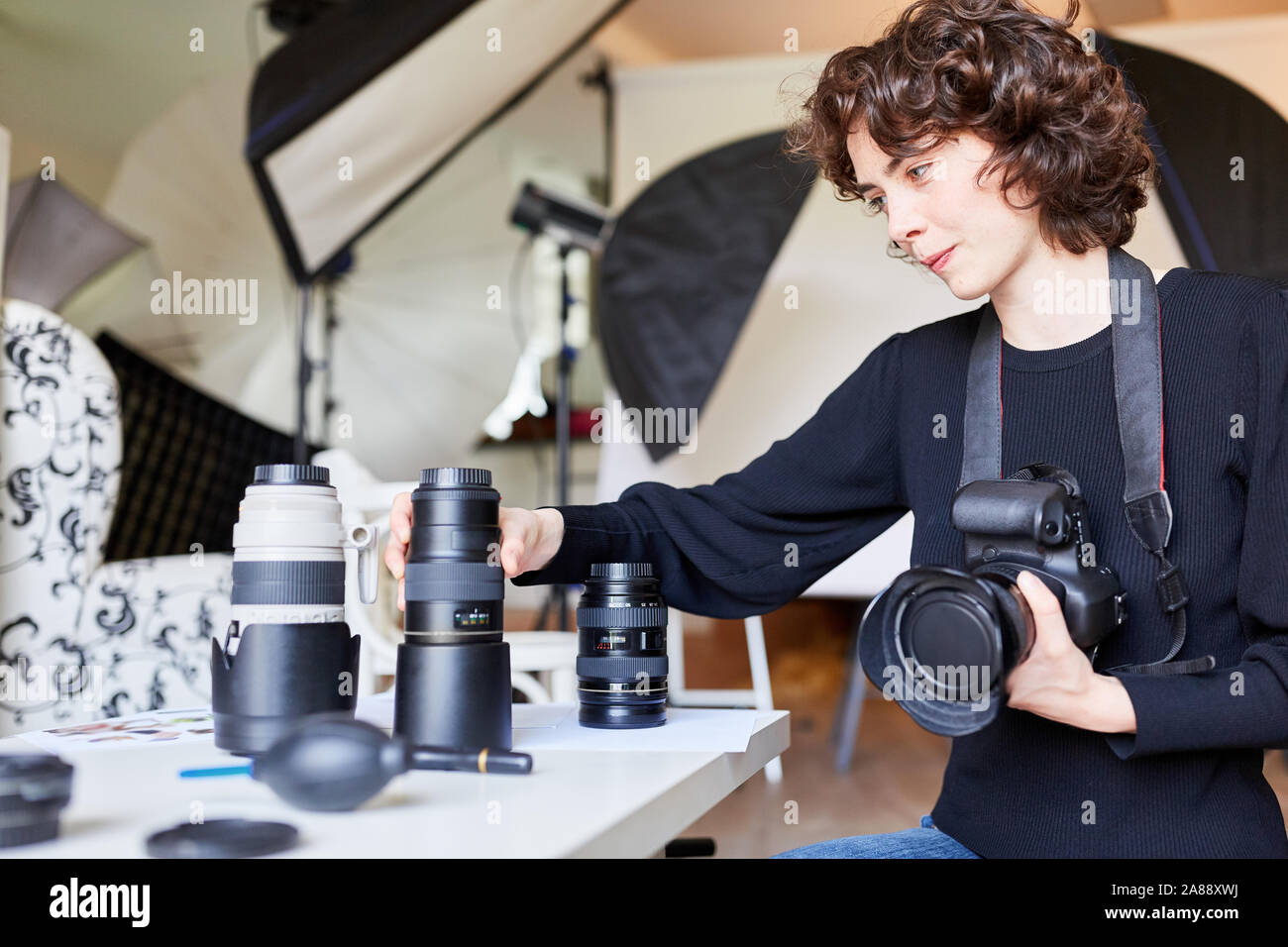 Professional photographer in the photo studio with camera and lenses ...