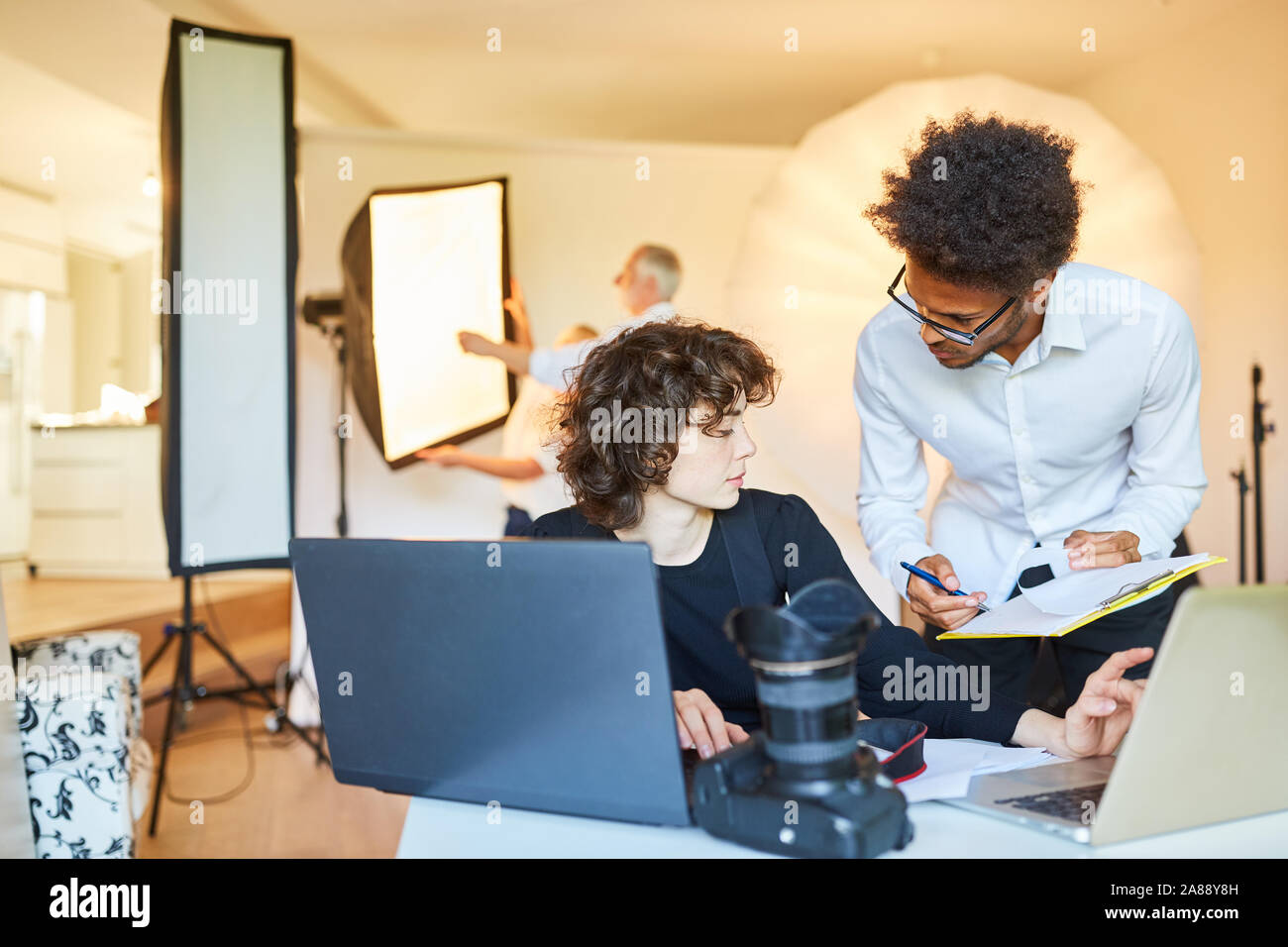 Photographer and photo assistant with clipboard at postproduction in ...