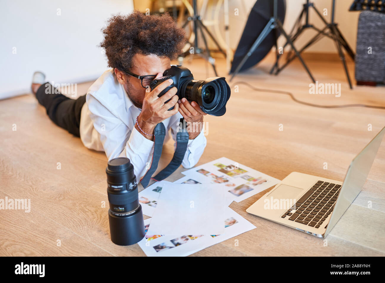 Young photographer in front of the laptop with camera and selection of ...