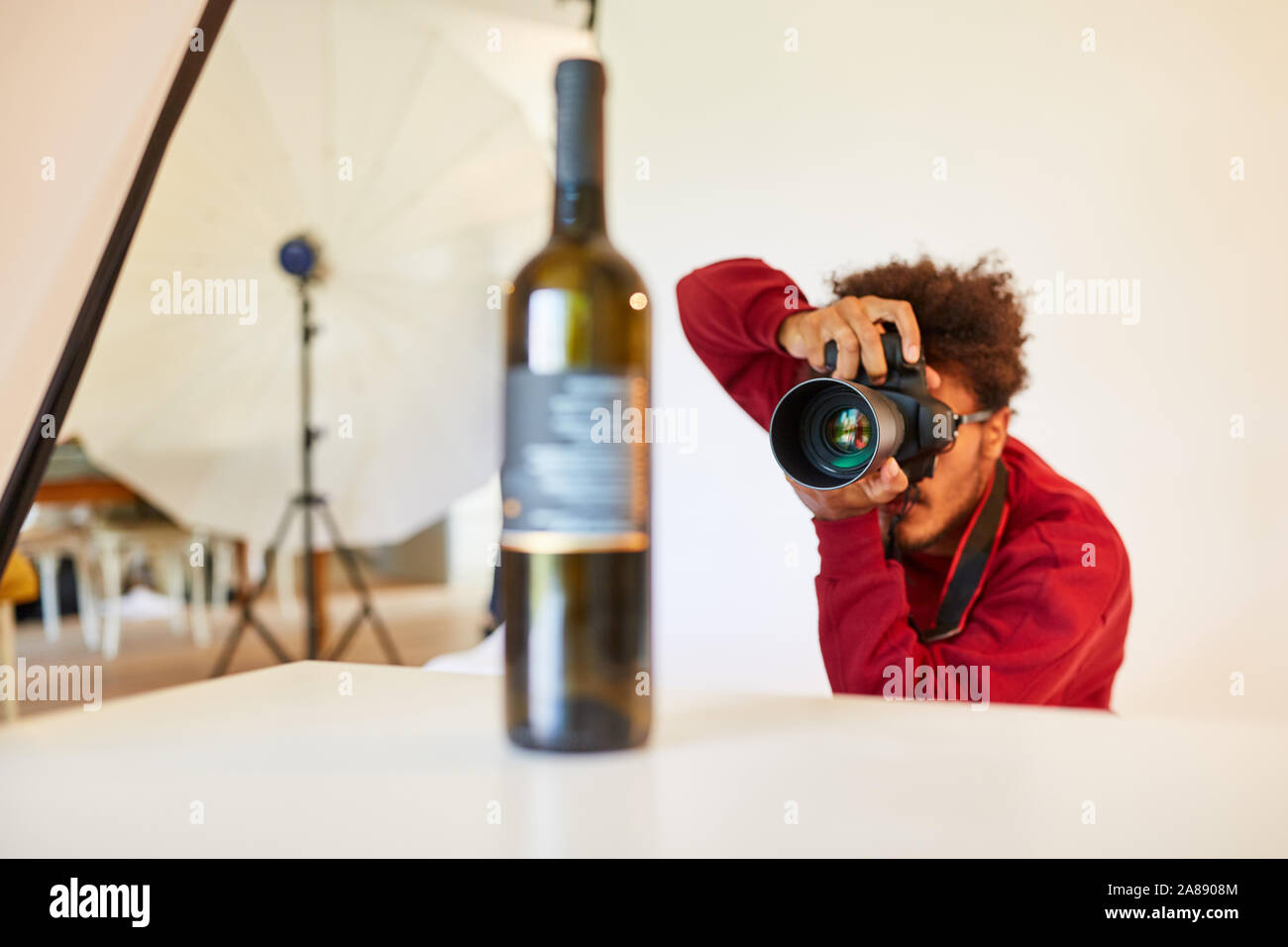 Photographer with SLR camera photographs a bottle as a product Stock ...