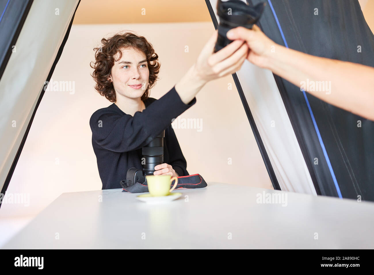 Young photo assistant in the photo school with camera. Lens in the ...