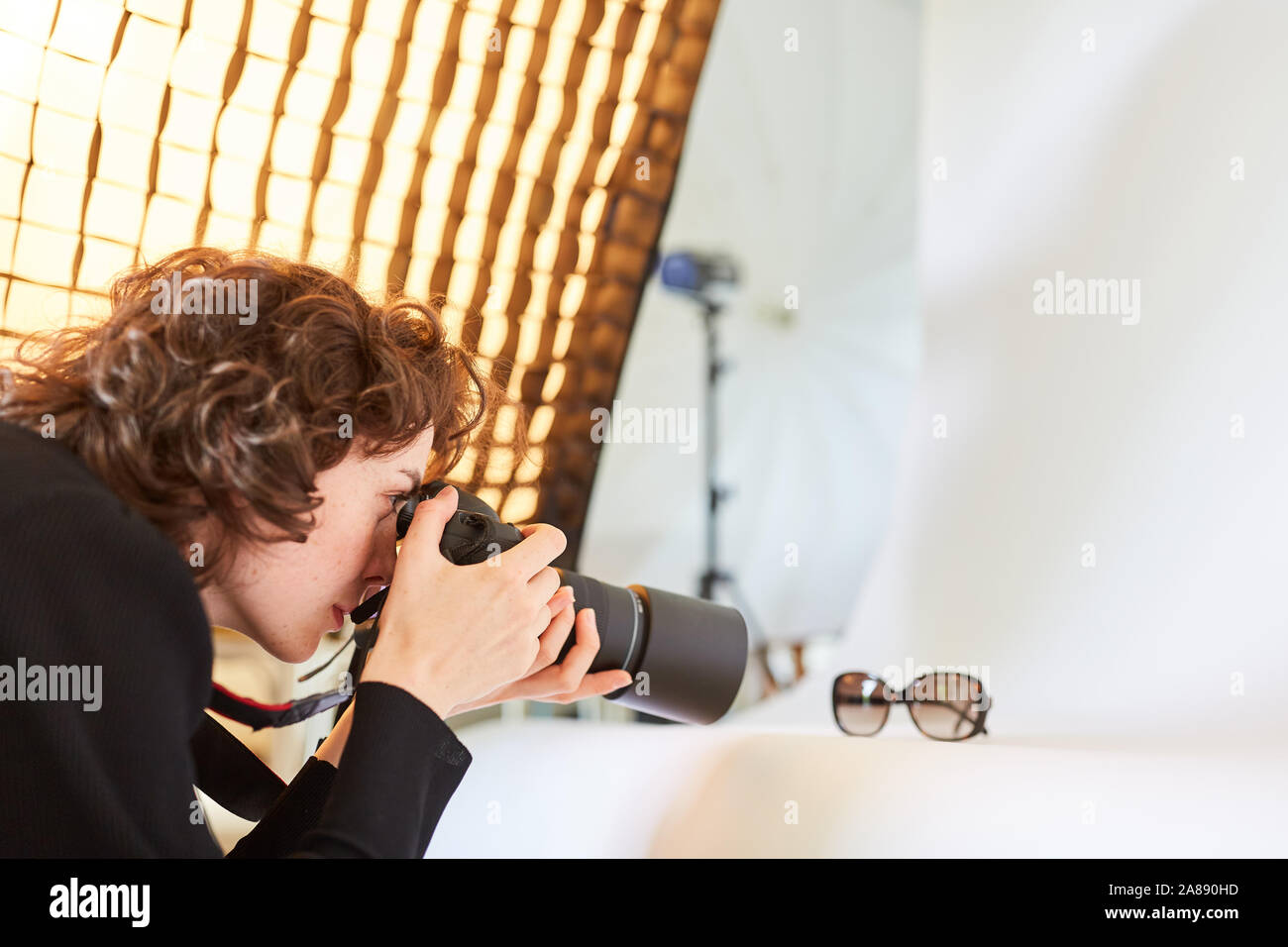 Photographer with camera photographs a pair of glasses for product ...