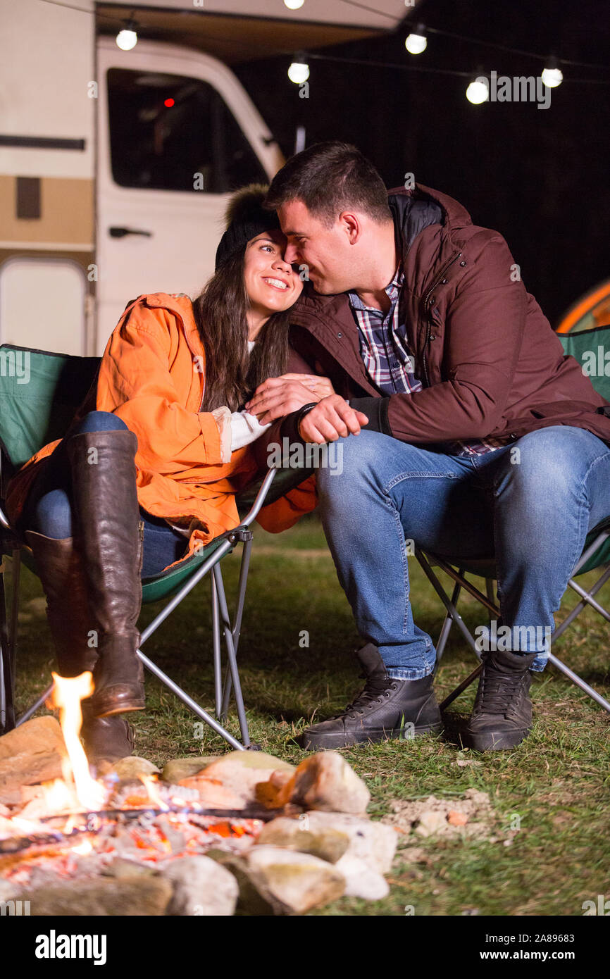 Beautiful couple recreating along campfire in the mountains with their ...