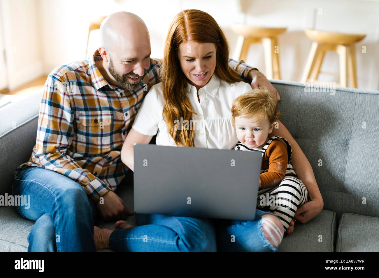 Family using laptop on sofa Stock Photo - Alamy