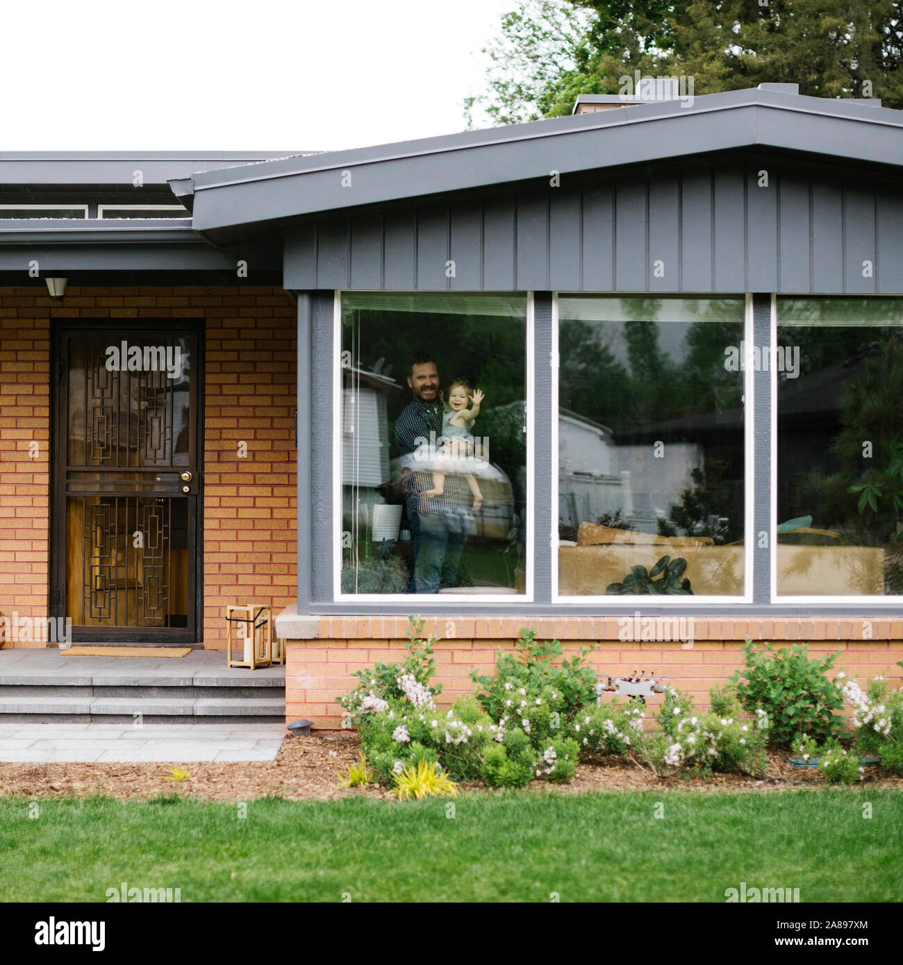 Father holding his daughter behind window of house Stock Photo - Alamy