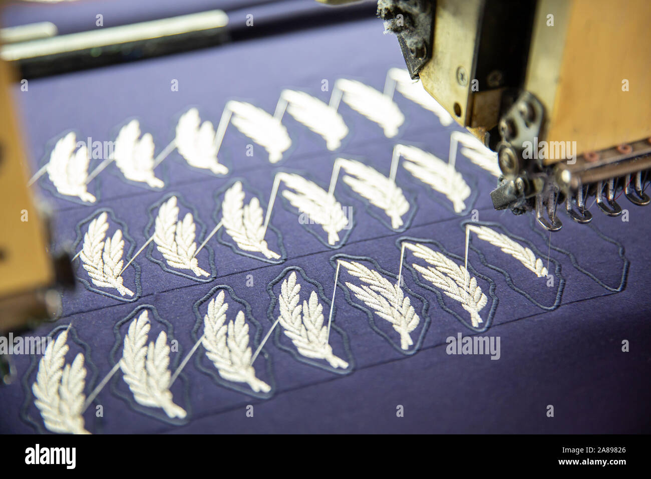 Close up with embroidery machine in working process. Blue material and ...