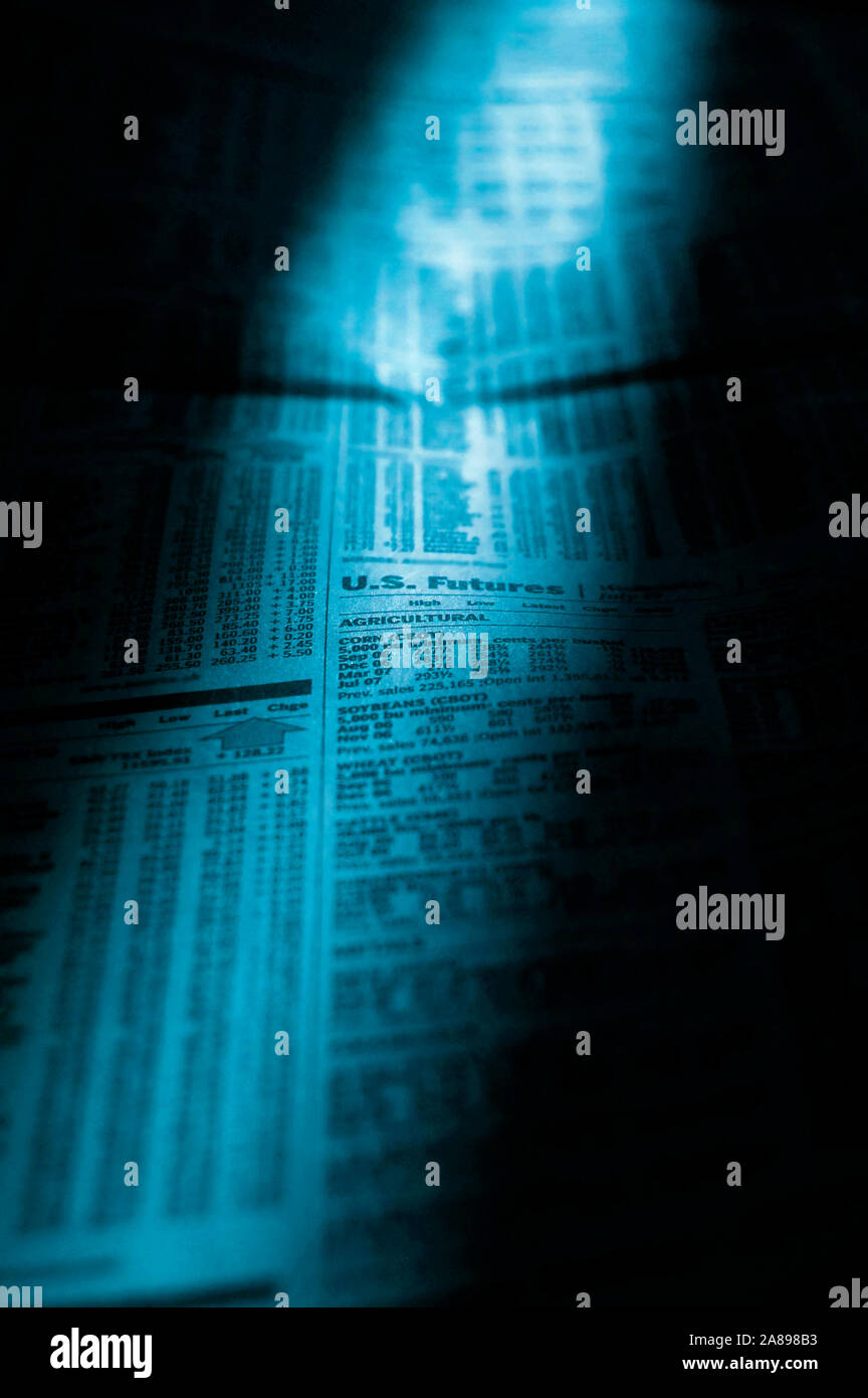 financial newspaper with a beam of light falling on it in green light ...