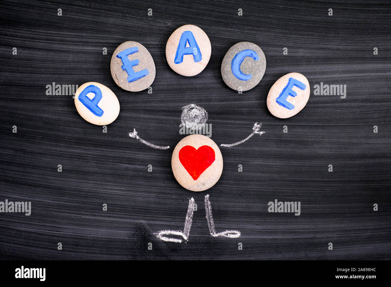 Pebble with heart symbol inside chalk drawing of man and letters PEACE ...