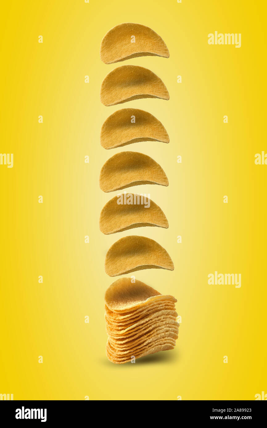 Gourmet potato crisps falling down against a yellow background with ...
