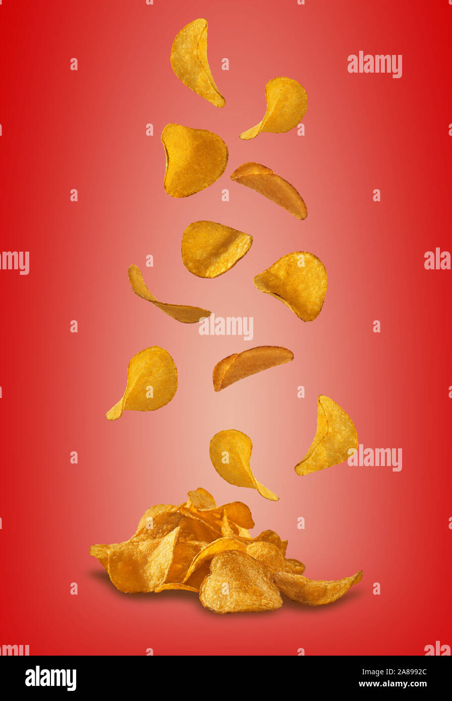 Delicious potato crisps falling down against a red background with copy ...