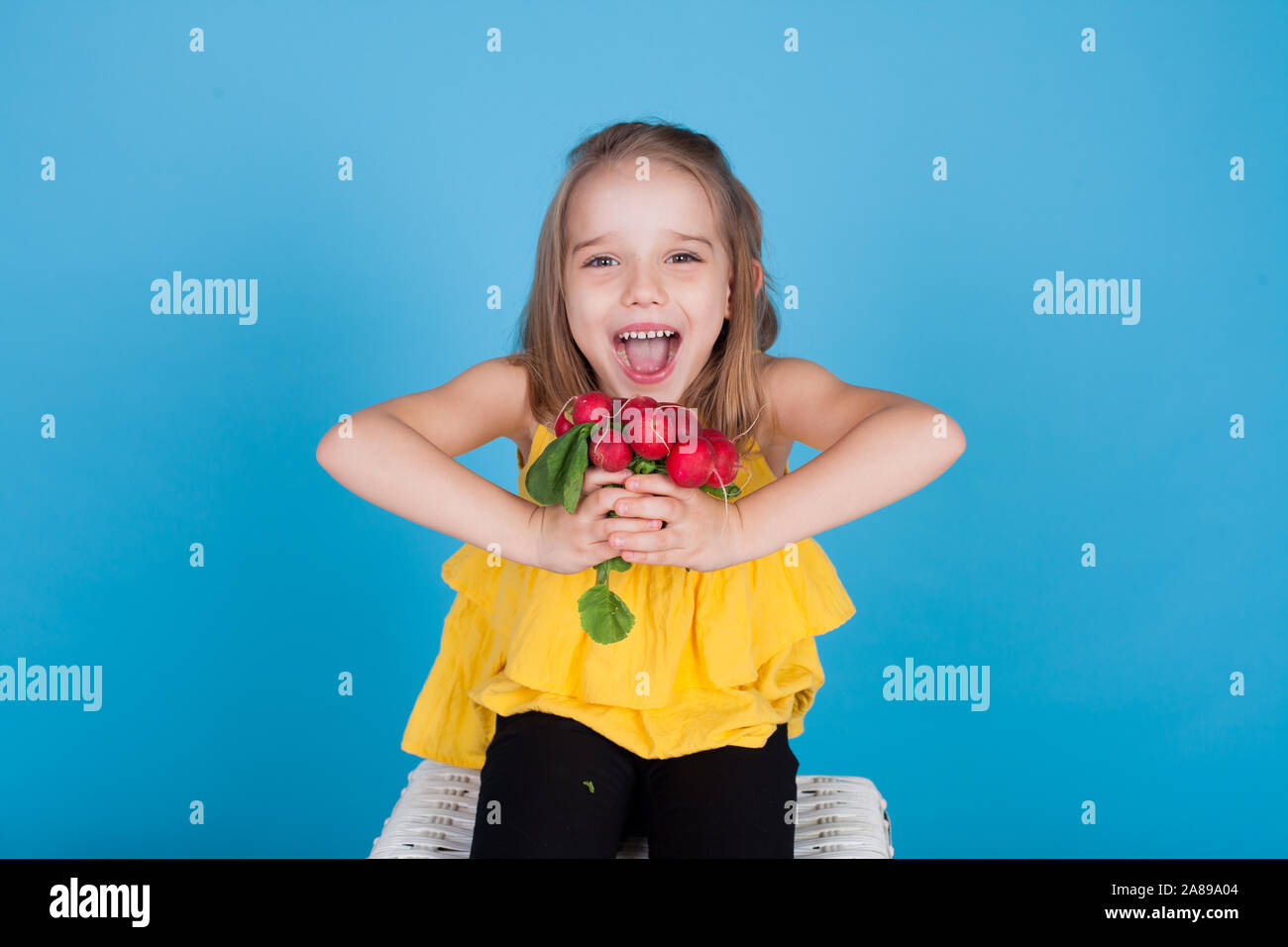 little girl with edible vegetables on a blue background Stock Photo - Alamy