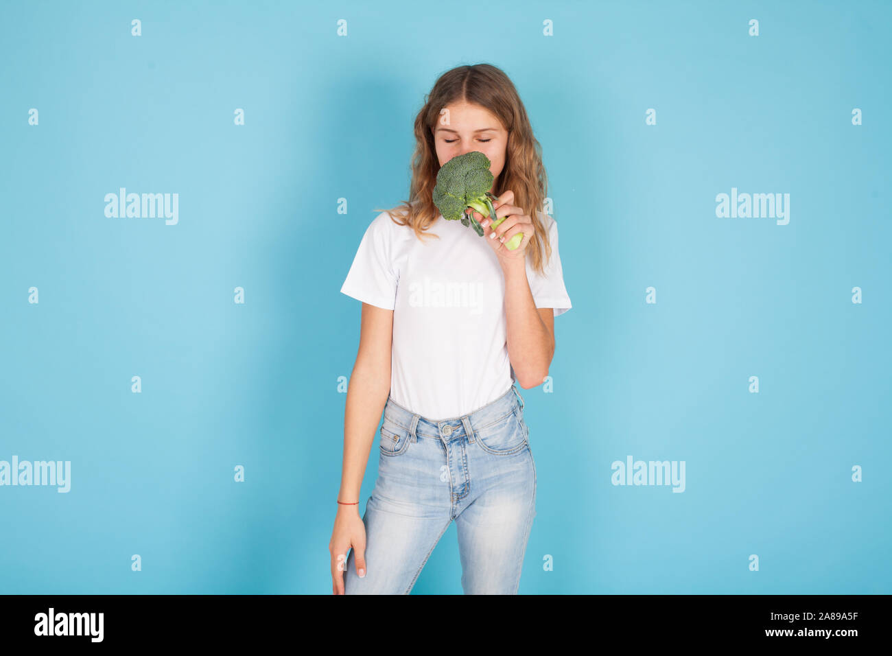 little girl with edible vegetables on a blue background Stock Photo - Alamy