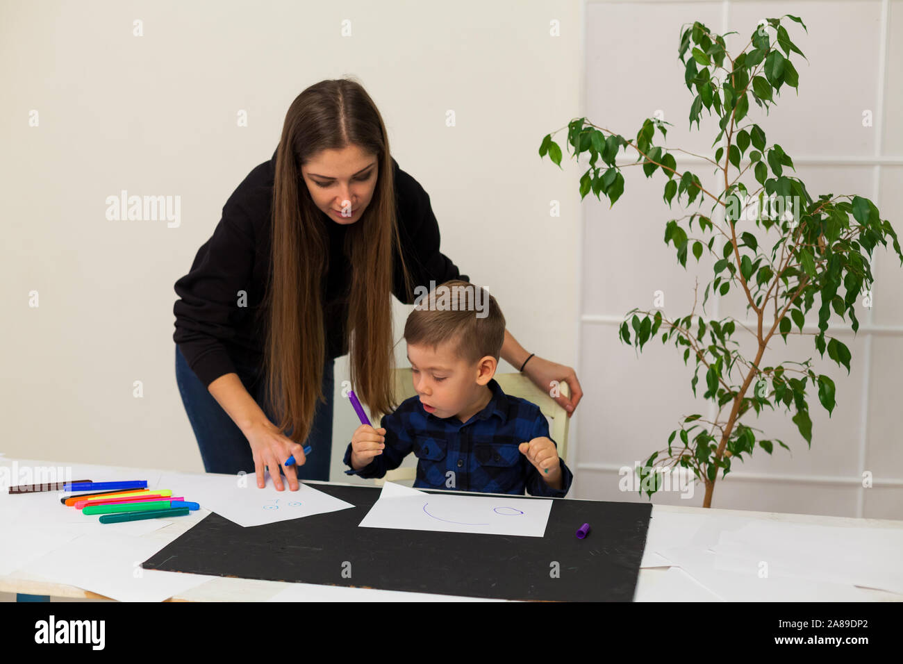 Woman teacher teaches little boy to draw Stock Photo - Alamy