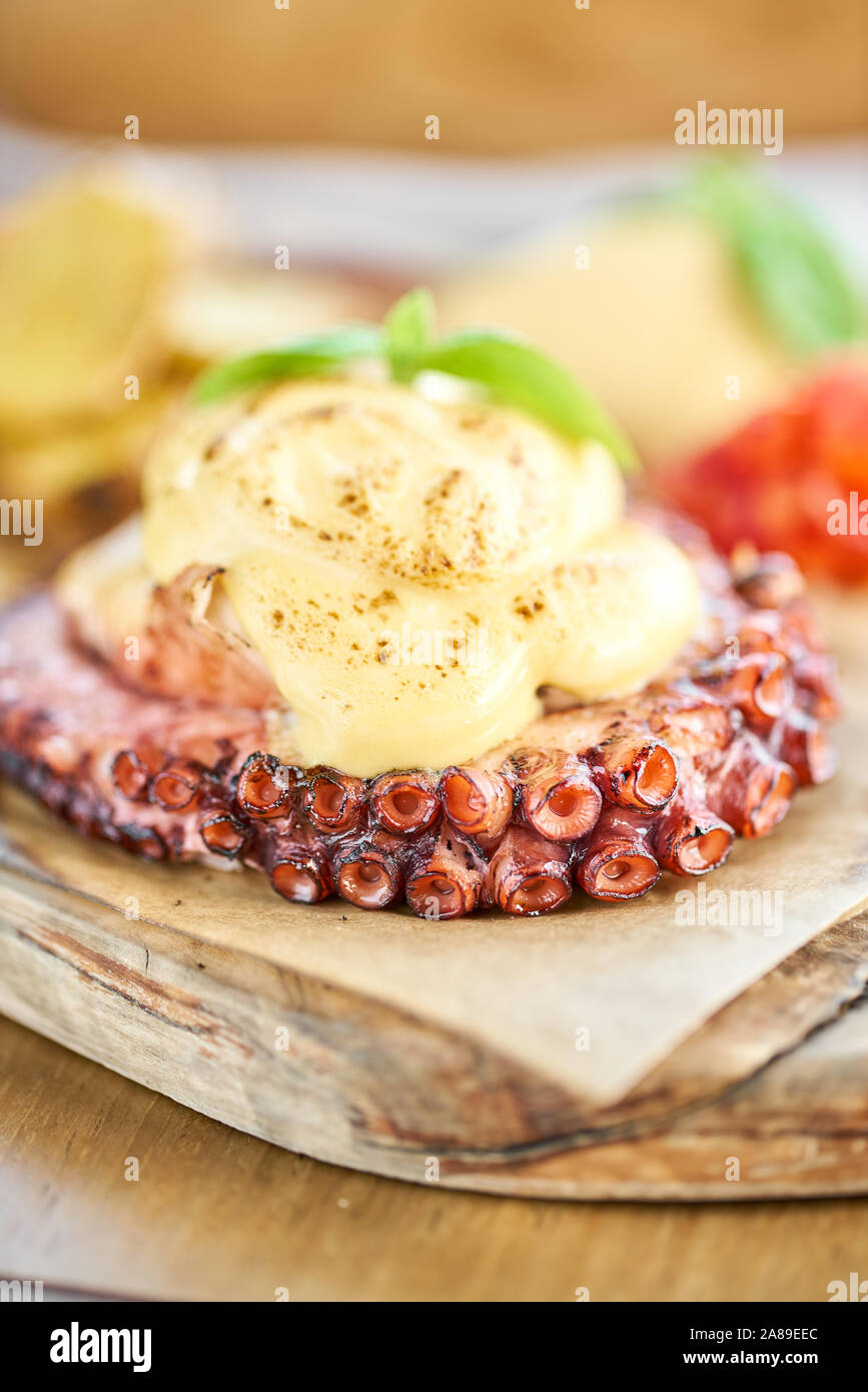 Close-up roasted octopus BBQ with Baked potato. Wooden plate ...