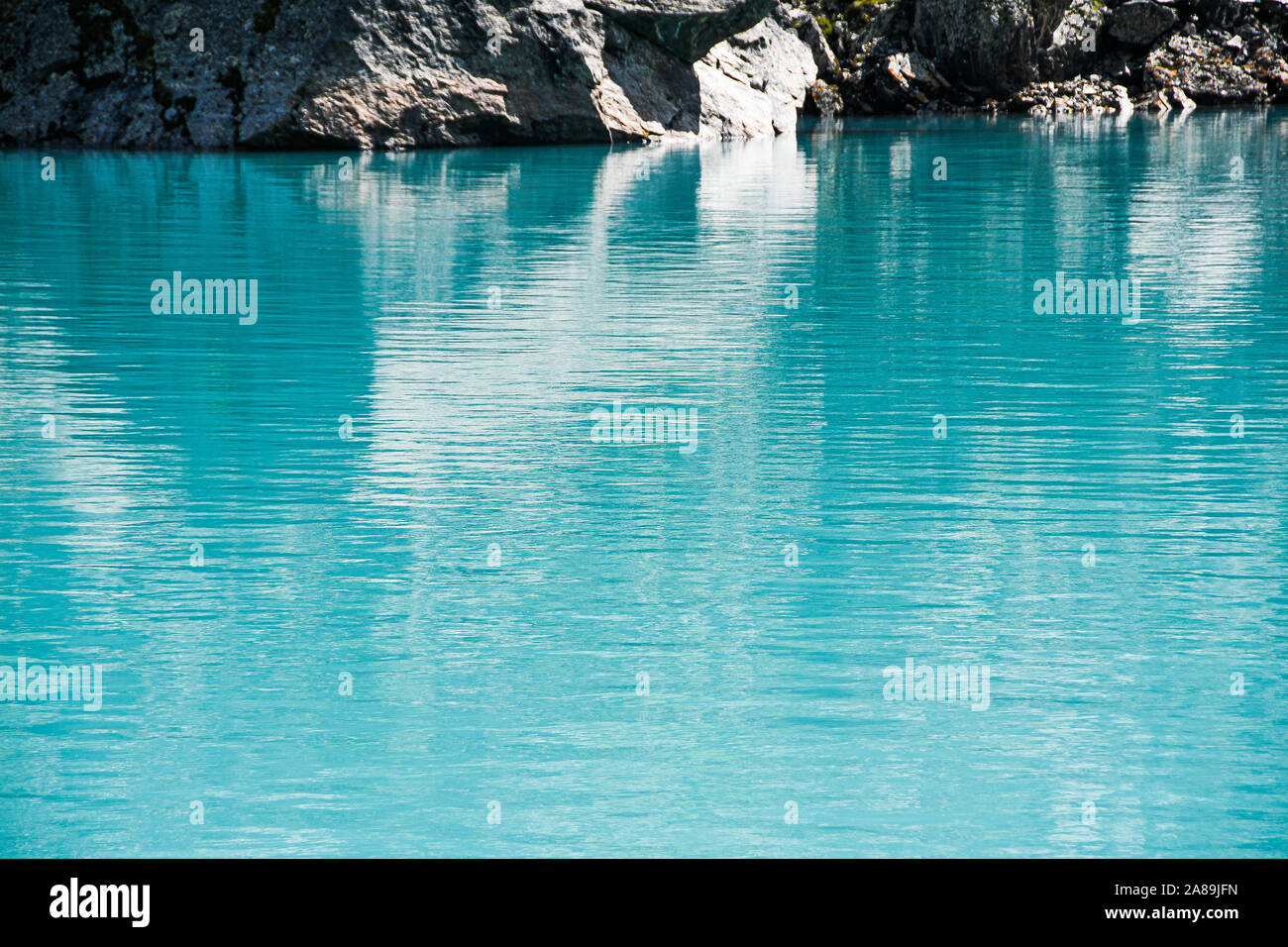 Rock on shore of blue sea. Turquoise mountain lake, the surface of ...