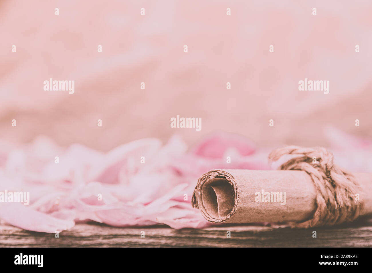 Roll of old paper on rose petals. Love letter, a wedding invitation ...