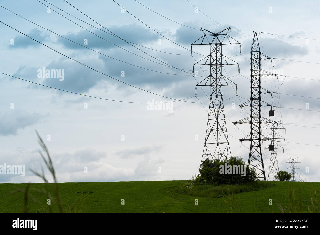 Power lines in green field on summer day. Transportation of electricity ...