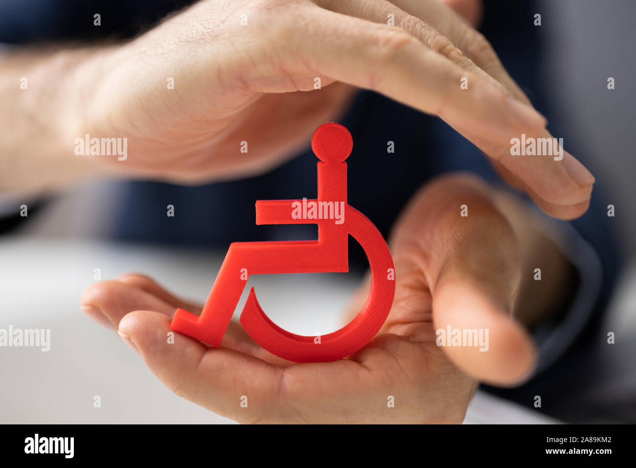 Close-up Of A Person's Hand Protecting Blue Cubic Block With Disabled ...