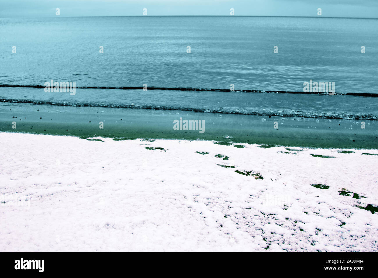 Onset of winter. The first snow on the beach. Waves lick the frost on ...