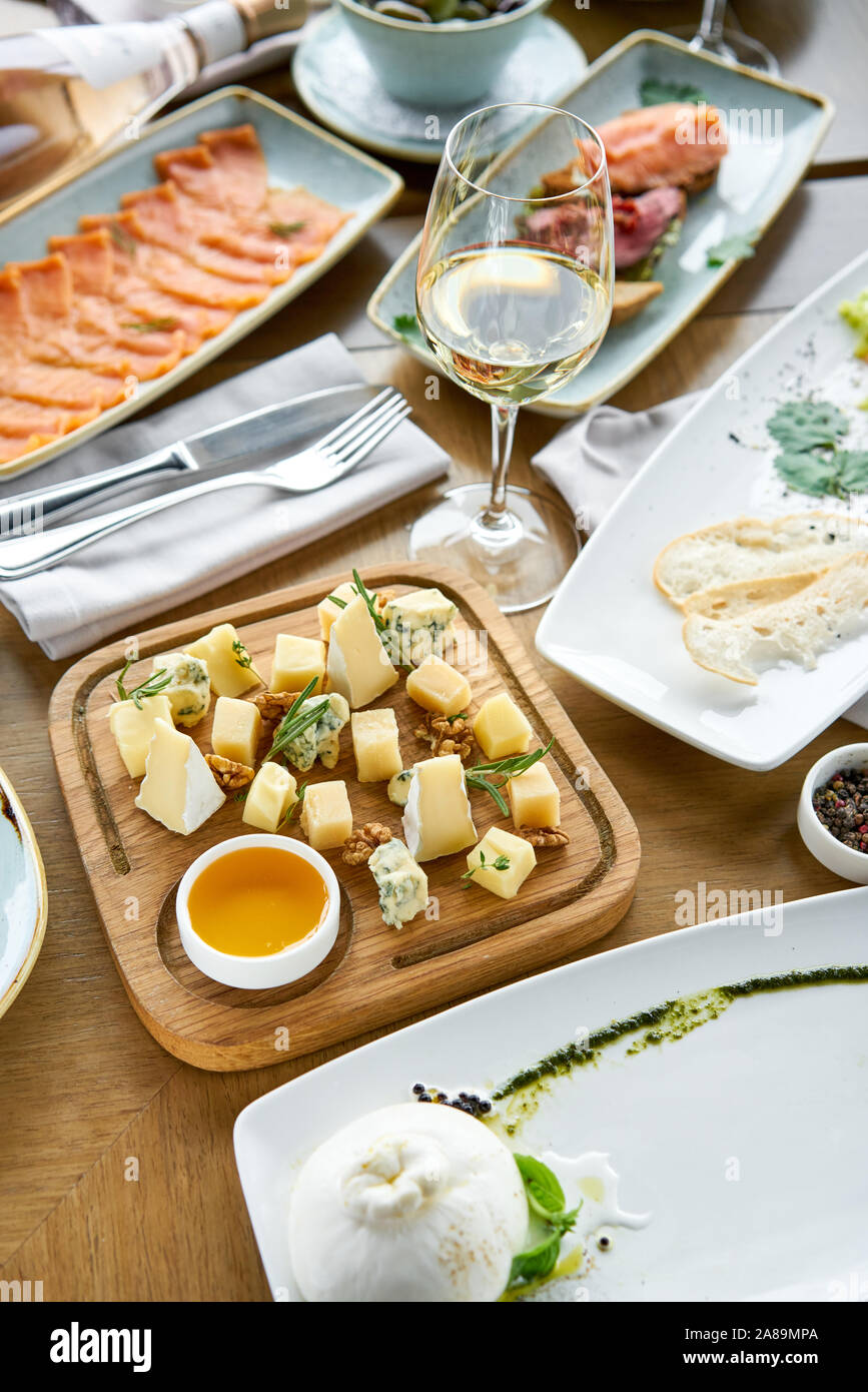 Cheese plate. Focus on delicious cheese mix with walnuts, honey on ...