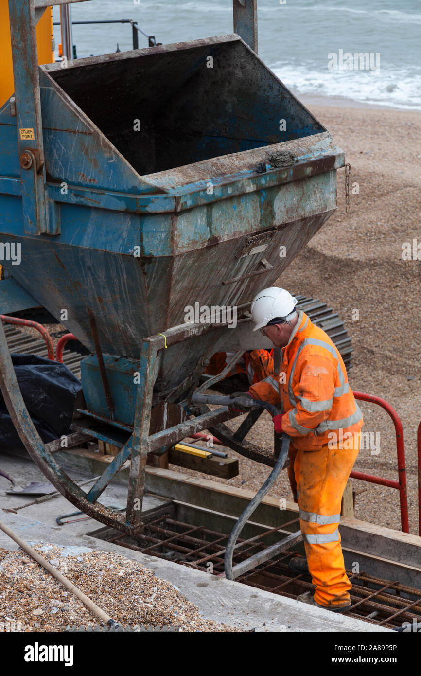 Workmen with heavy plant machinery repair the flood defence wall at ...