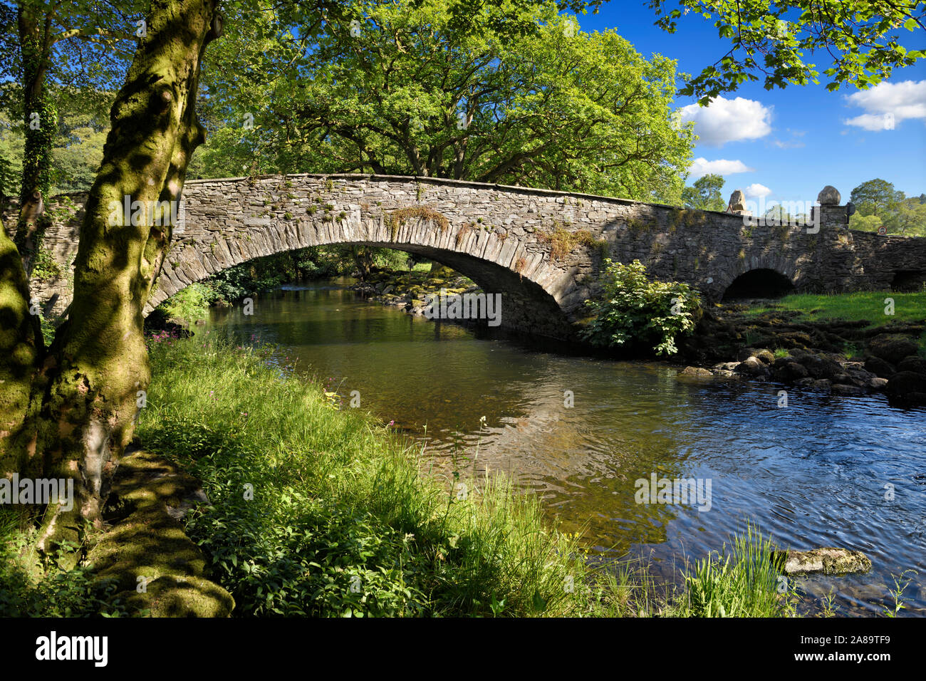 Stone arch Pelter Bridge in evening sun over the River Rothay at Rydal ...