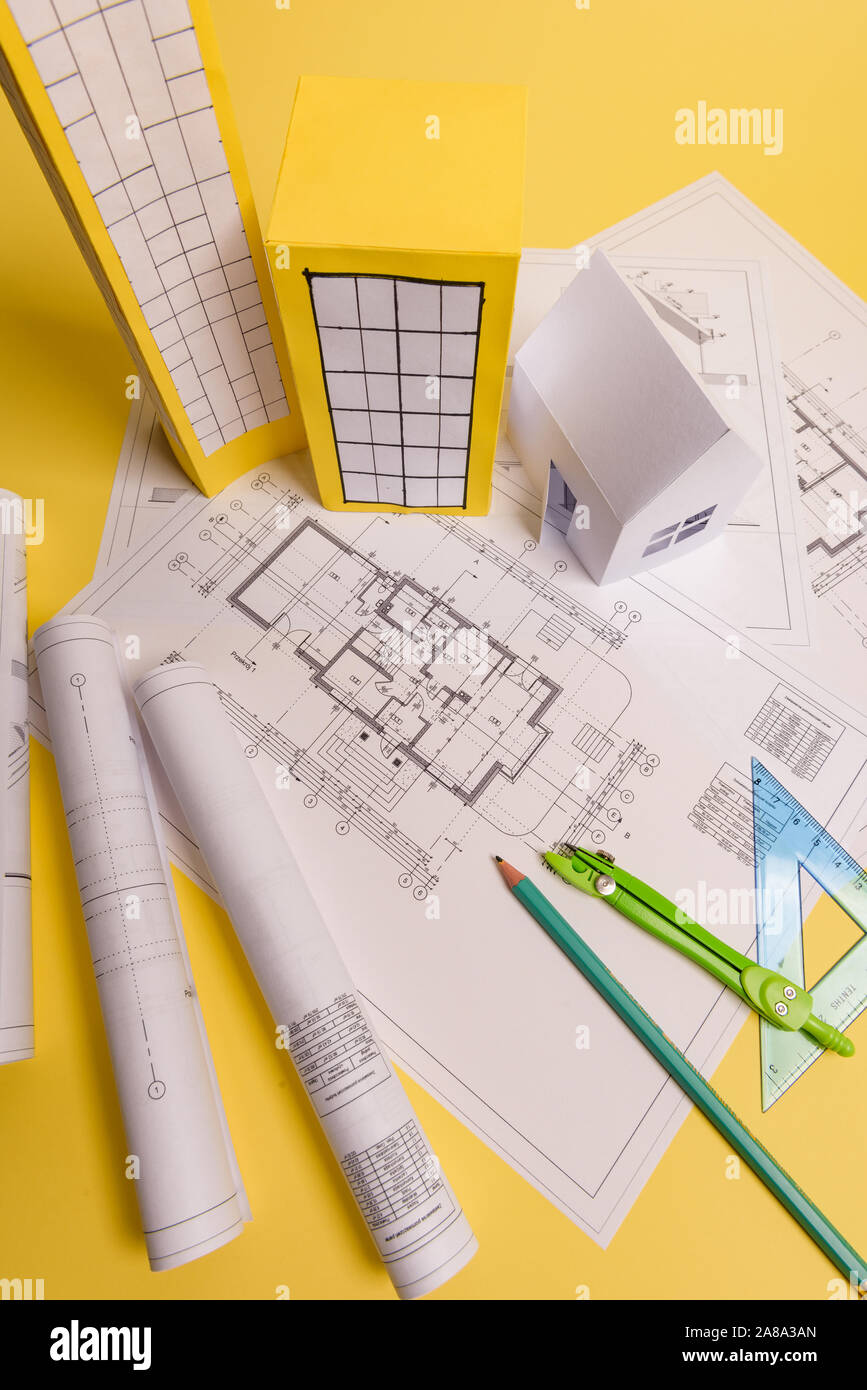 White family paper house, house projects plan and blueprints on yellow ...