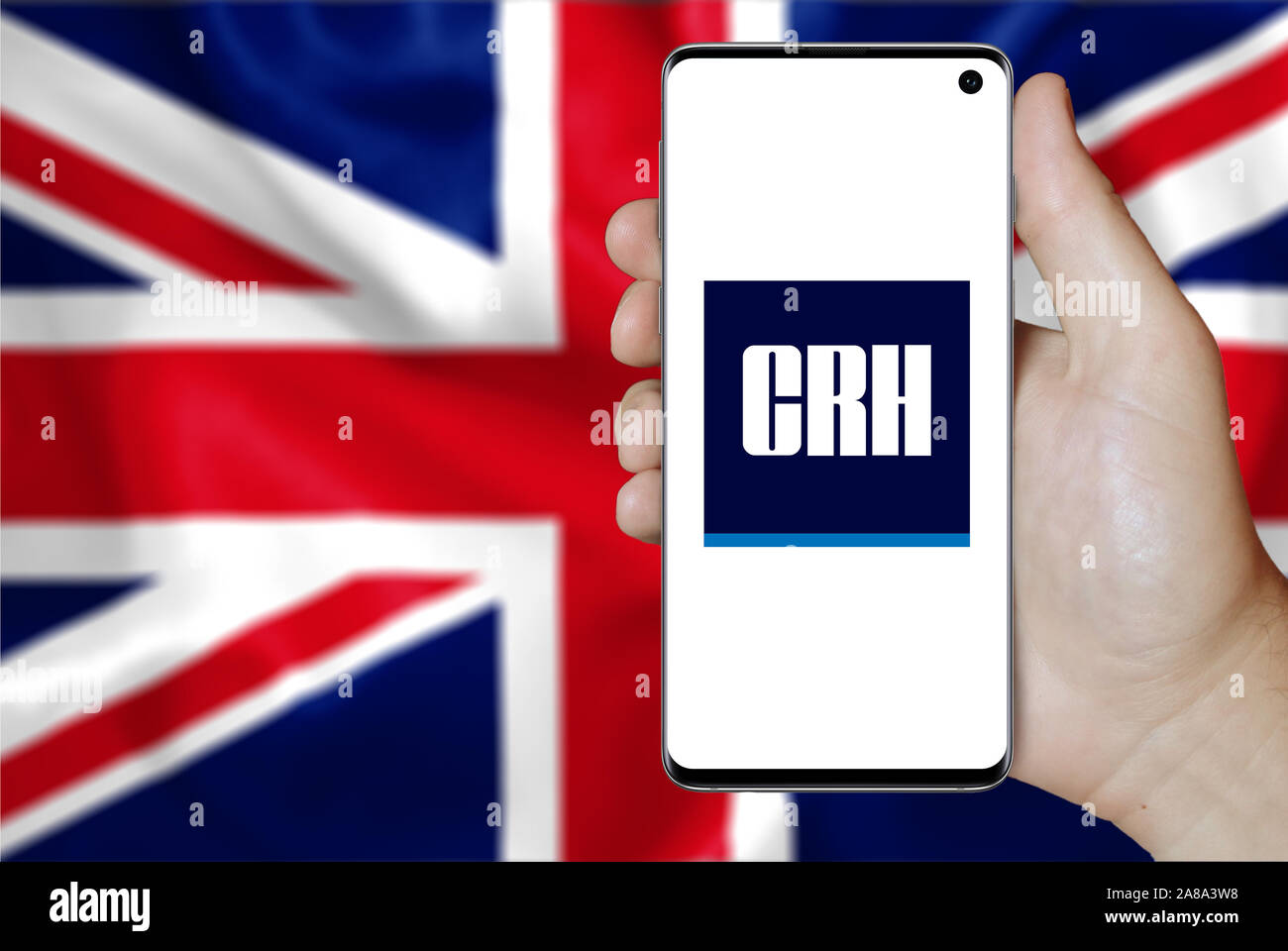 Logo of public company CRH plc displayed on a smartphone. Flag of UK ...