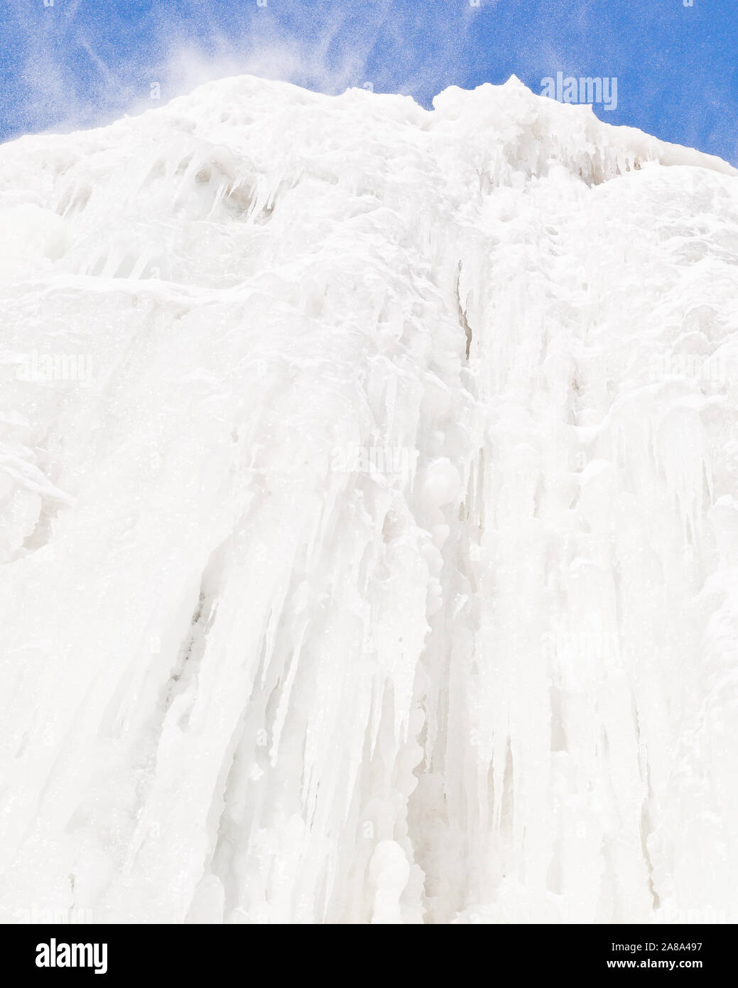 A dramatic sheer tall wall of white ice and blowing snow against a ...