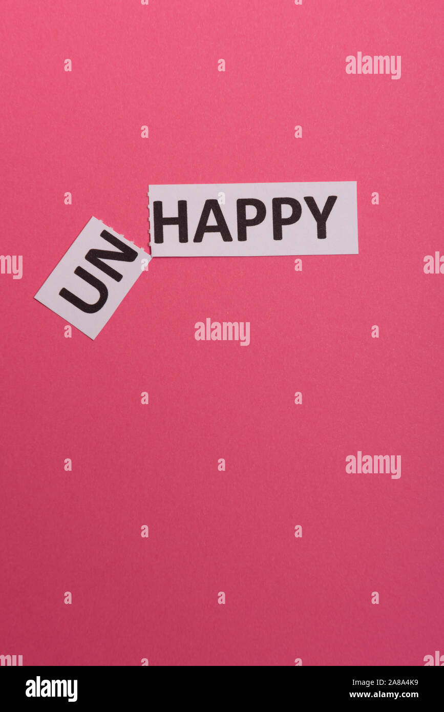 man hand holding card with text unhappy, cutting word 'un' so it ...