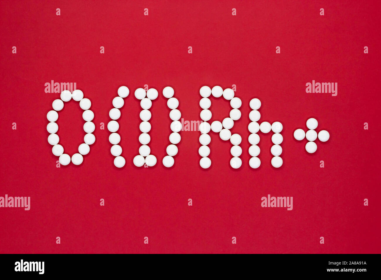 First blood type. Blood type symbol from white pills on a red ...