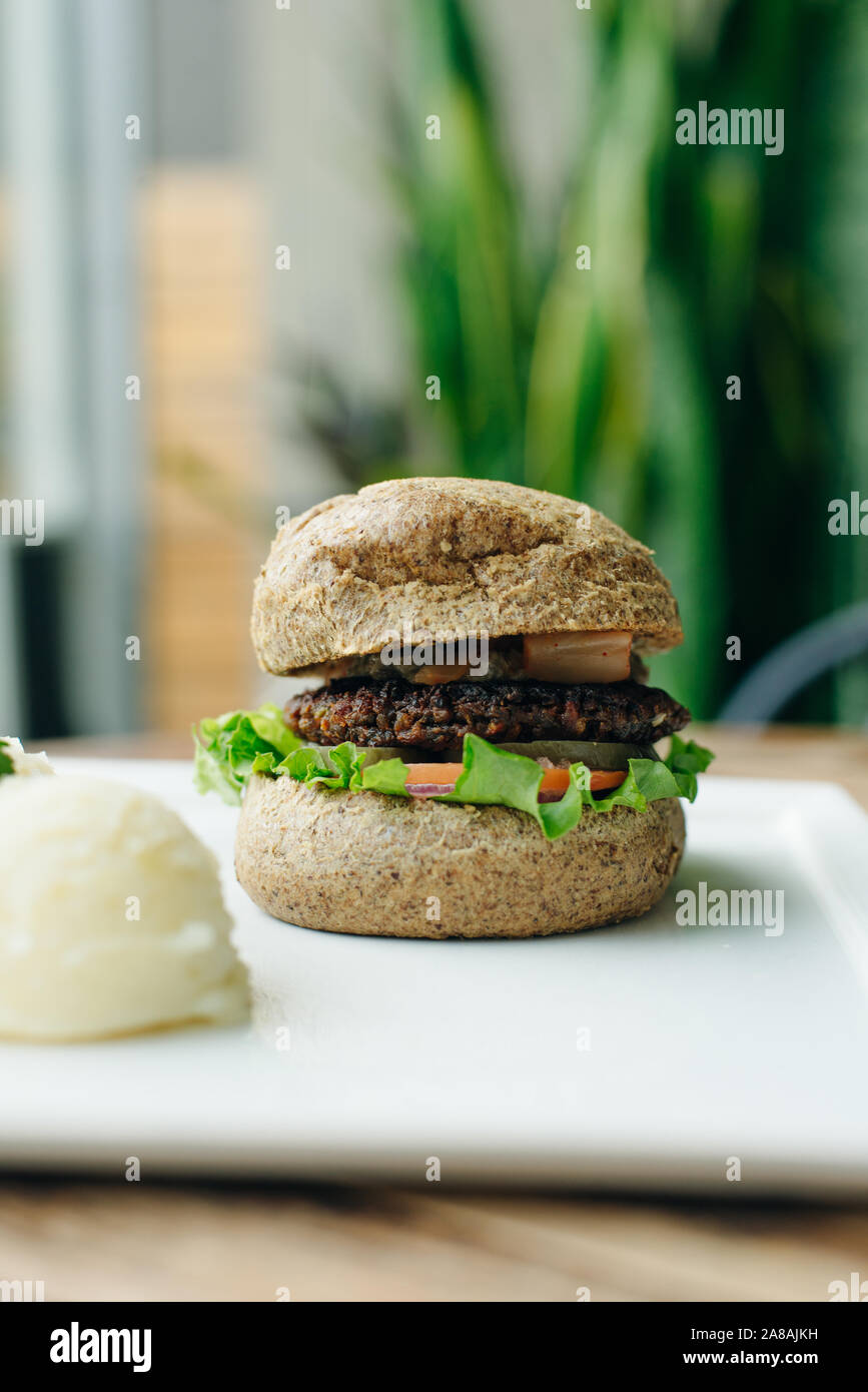 Vegan big bean burger with mashed potato in classic bun, served on ...