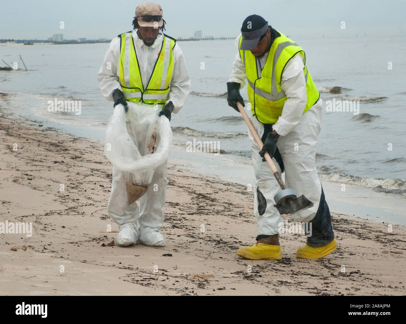Oil spill cleanup workers remove tar patties from the beach after the ...