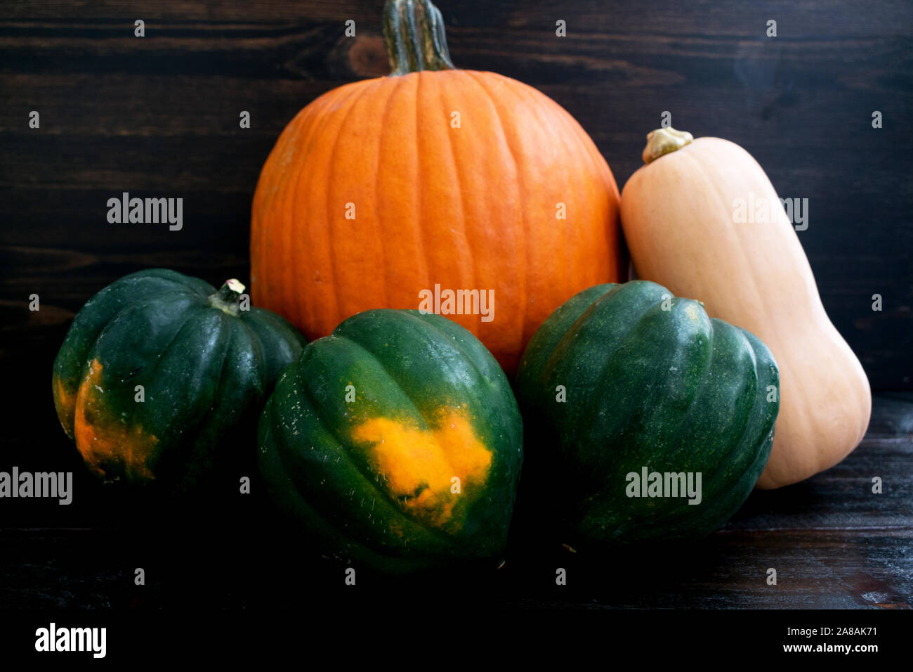 Rustic grouping of acorn squash, butternut squash, and a pumpkin on a ...