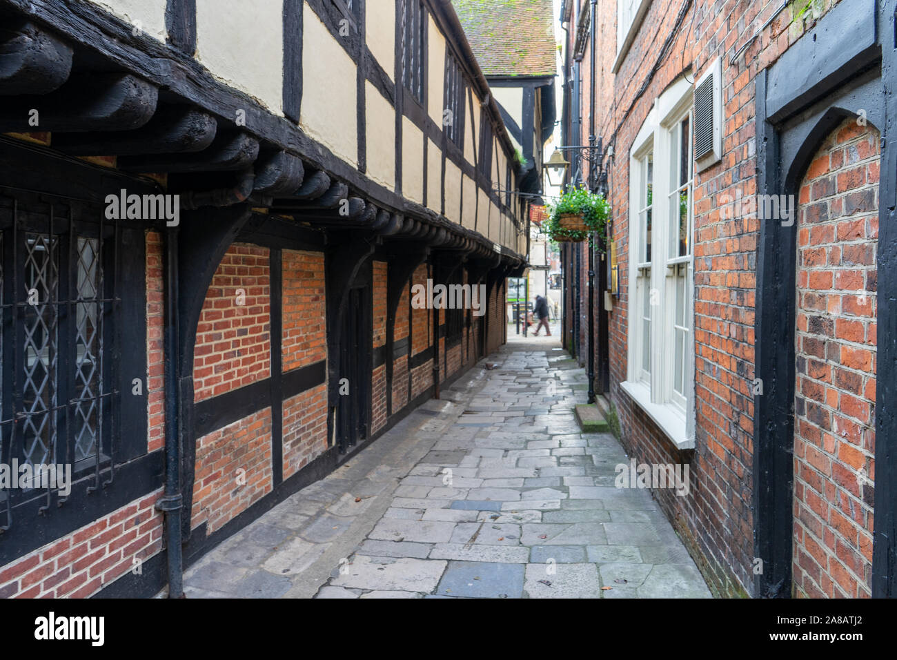A paved alleyway in an old english town with a tudor building alongside ...